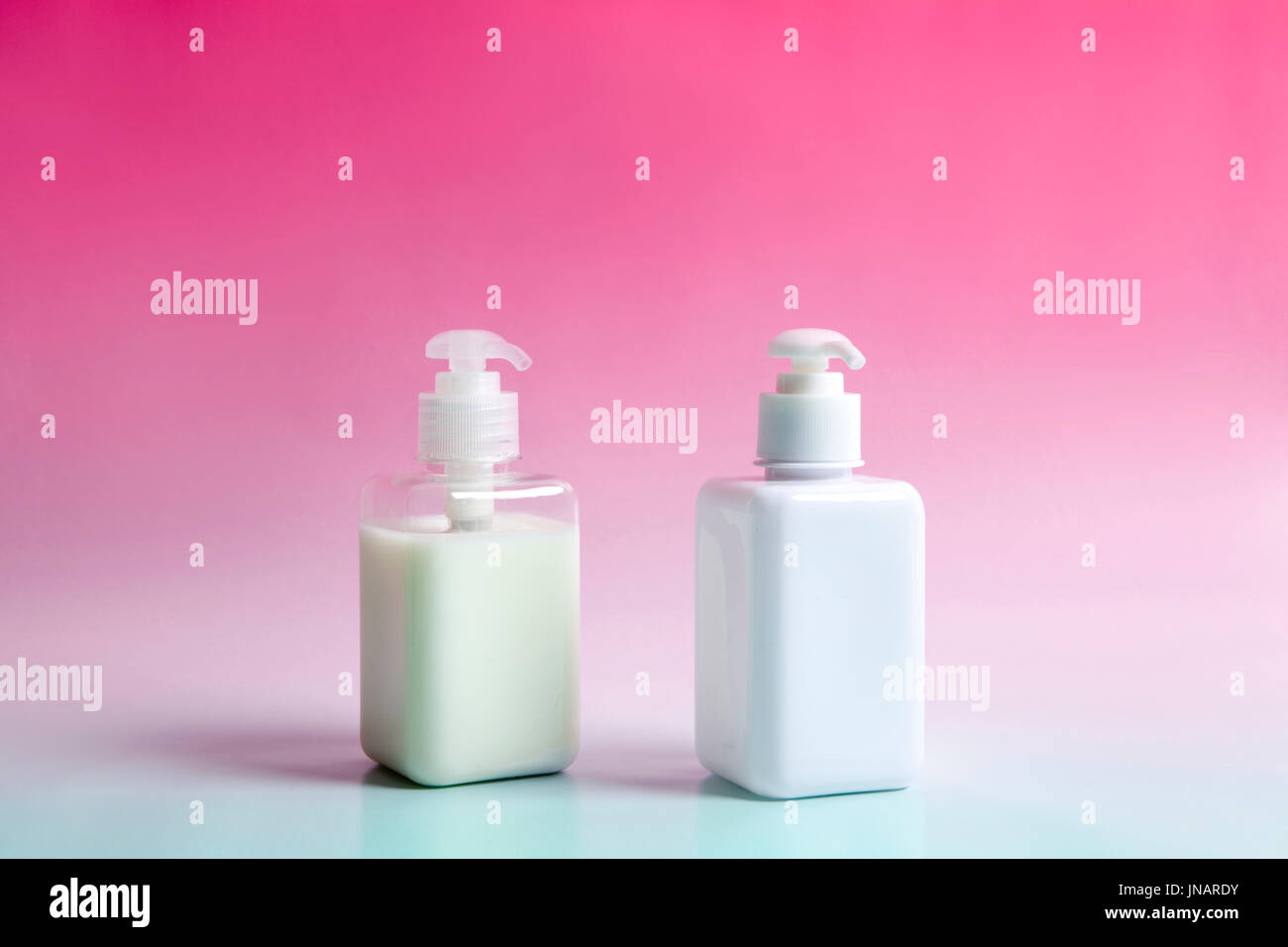 two rectangular pump bottles : white and transparent, on a gradient ...
