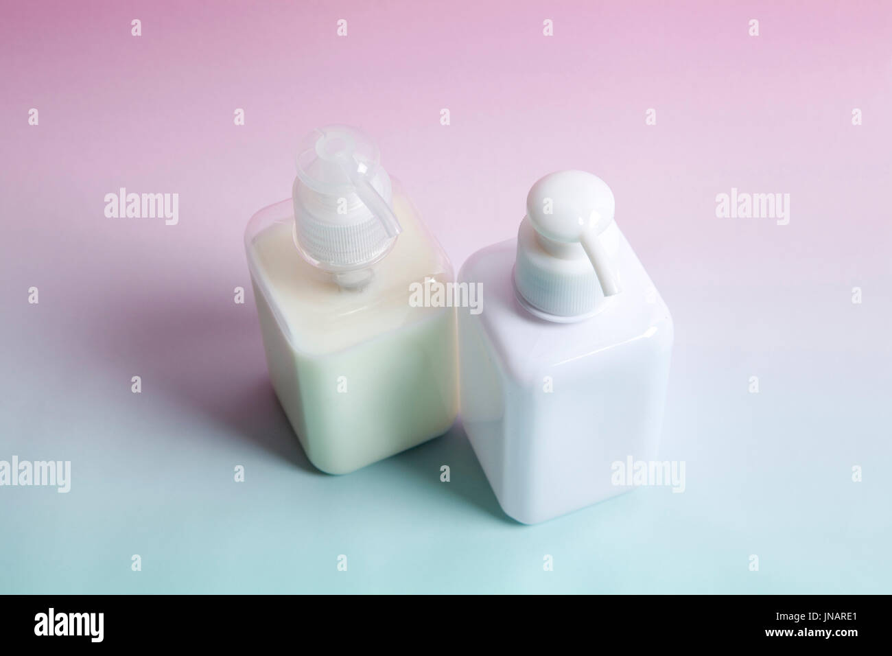 two rectangular pump bottles : white and transparent, on a gradient ...