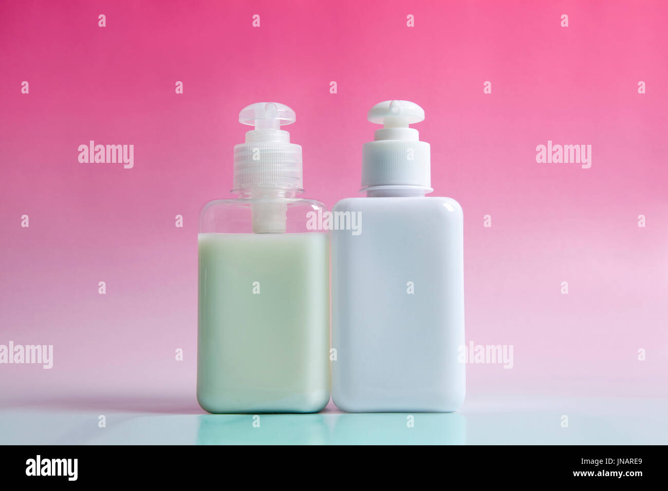 two rectangular pump bottles : white and transparent, on a gradient ...