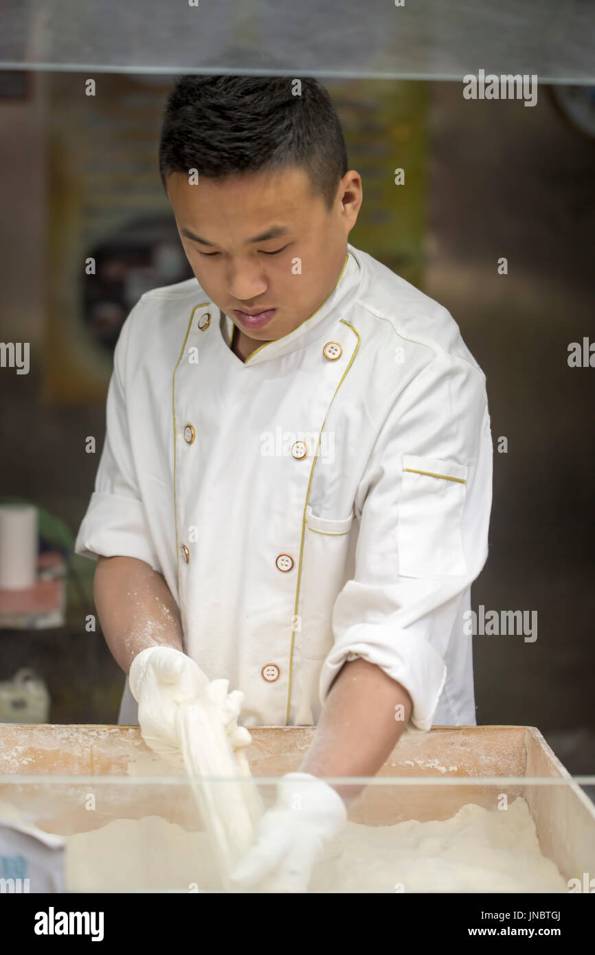 Chinese salesman preparing longxu candy on traditional food market ...