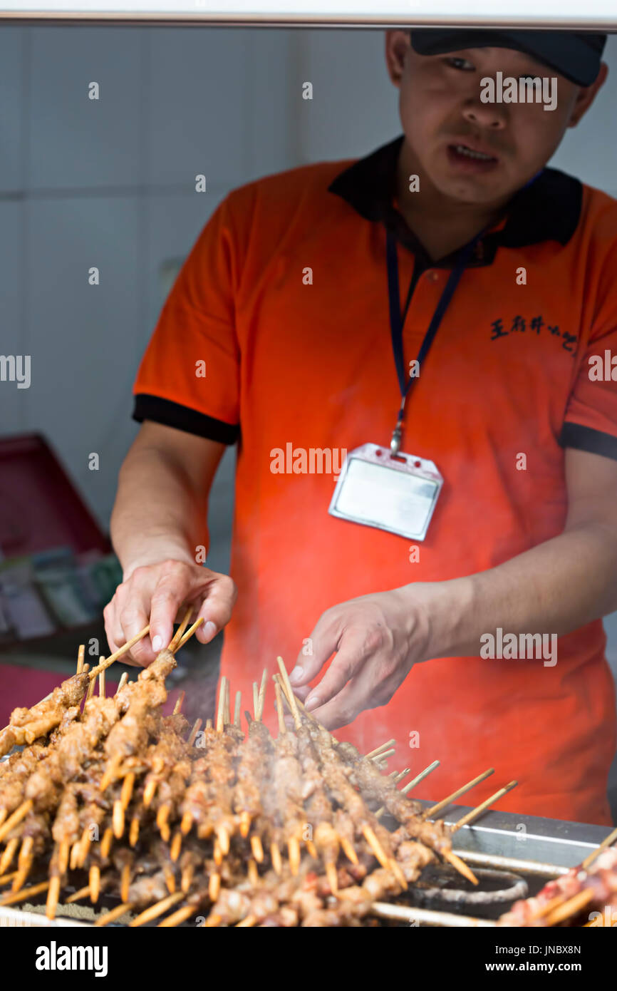 Chinese salesman preparing meat on traditional food market. Wangfujing ...