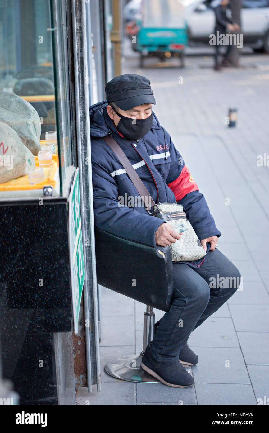 Chinese salesman asleep at work, holding banknote in his hand, Beijing ...