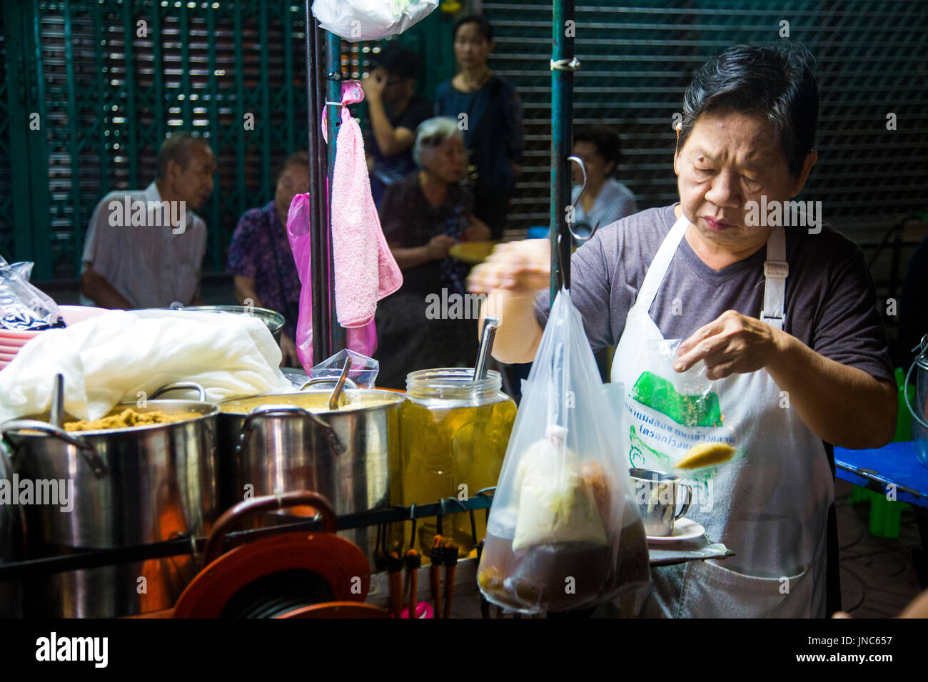 Thai man preparing food at a stall night food market in Chinatown ...
