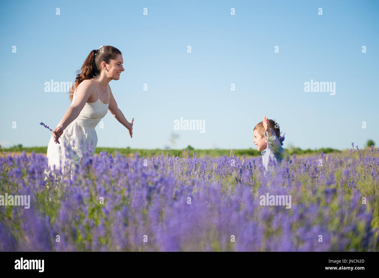 happy child running into the arms of smiling mother on the flower field ...