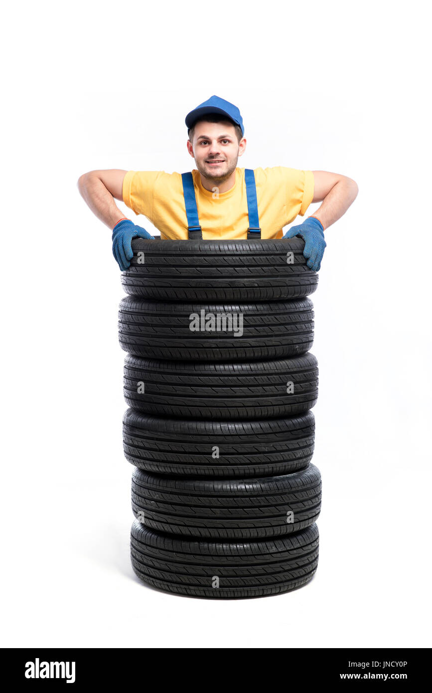 Tyre service, worker is standing inside a pile of tires, white ...