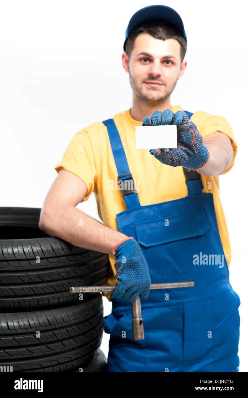 Tyre service, worker in blue uniform holds tire and empty businesscard ...