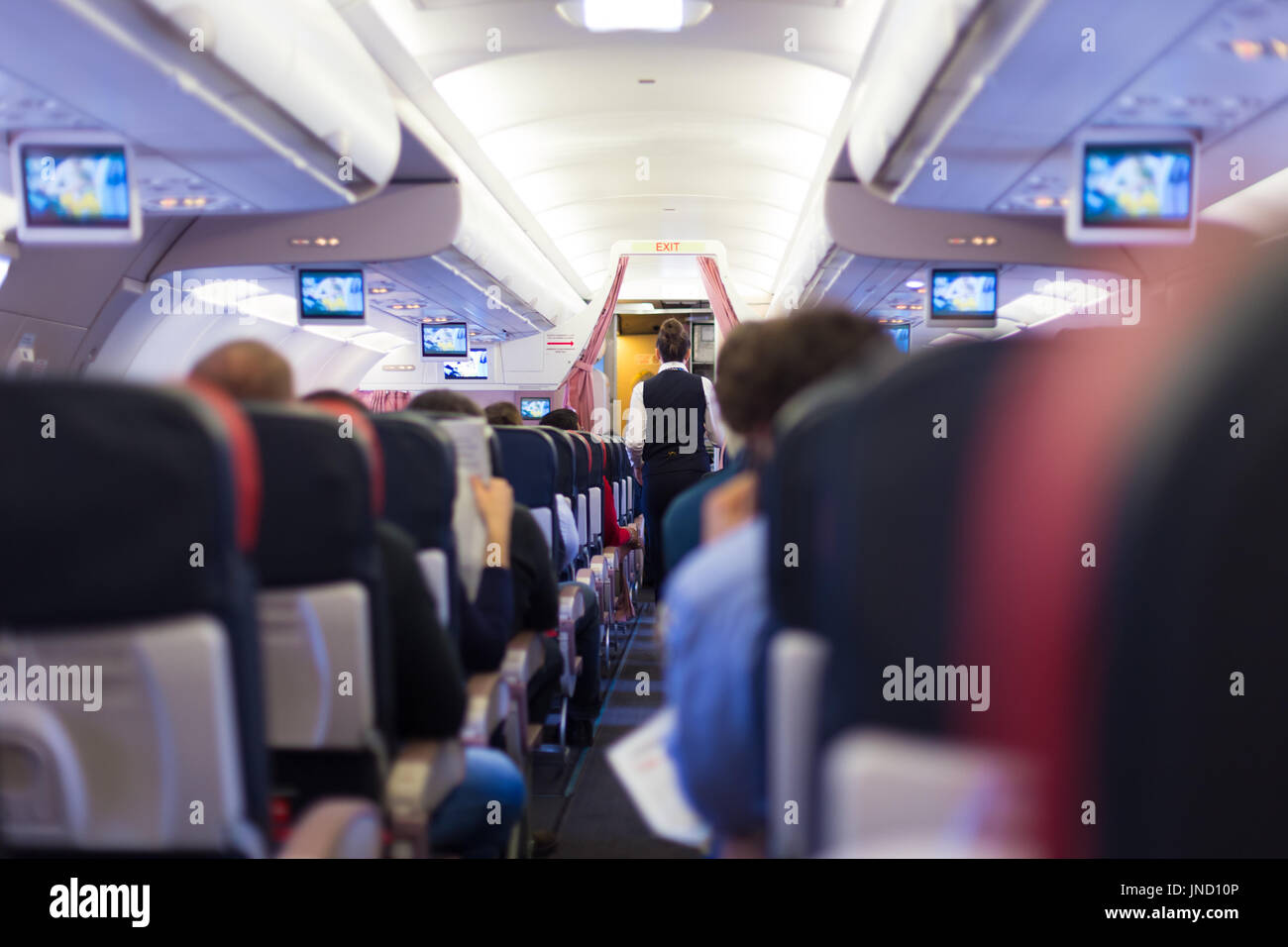 Interior of commercial airplane with passengers on seats during flight ...