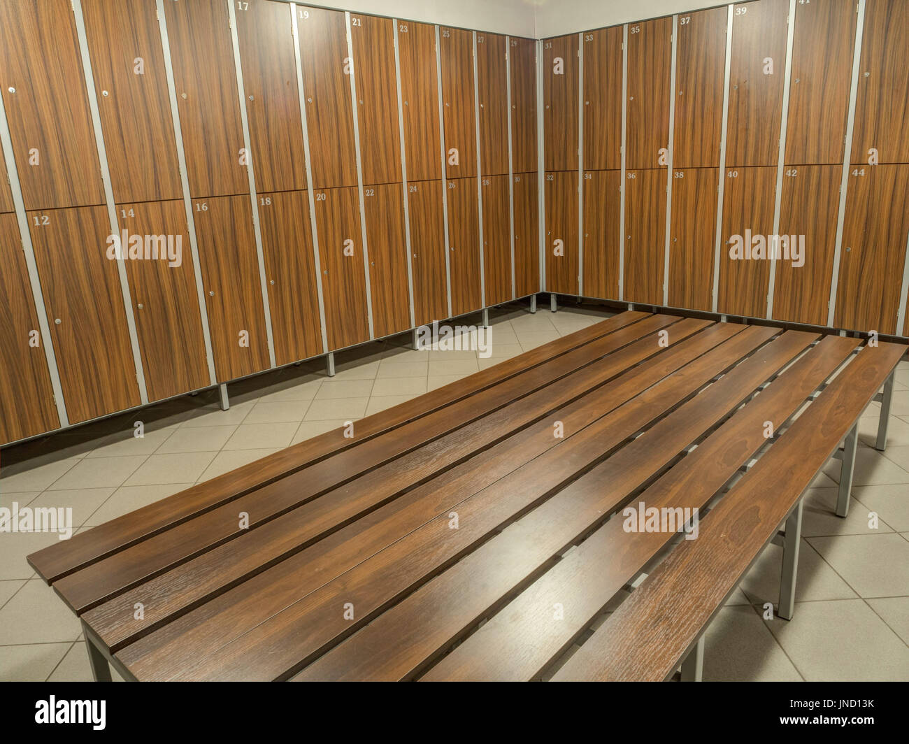 The row of wooden cabinets and a wooden bench in a fitness club ...