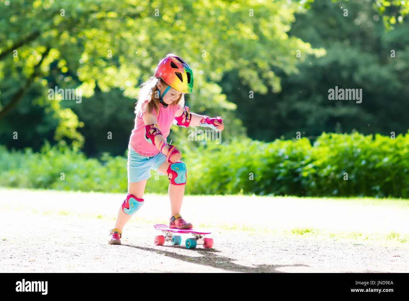 Child riding skateboard in summer park. Little girl learning to ride ...