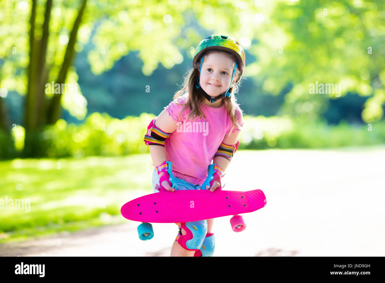 Child riding skateboard in summer park. Little girl learning to ride ...