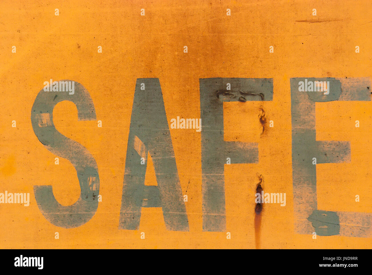 Word SAFE in capital letters stenciled in green on rusty yellow ...