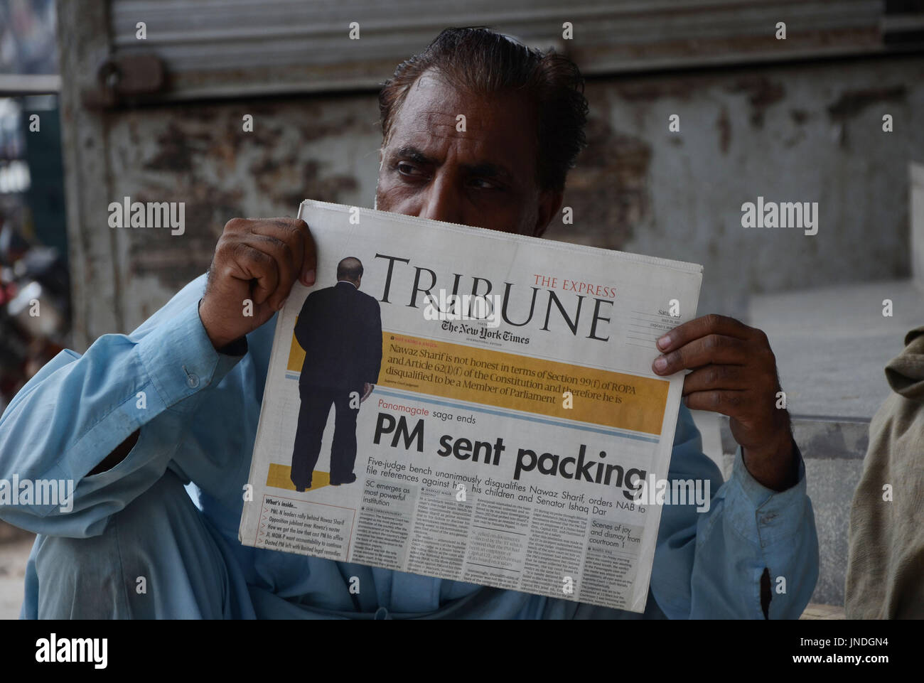 Pakistani man reads a newspaper with front page news of ousted ...