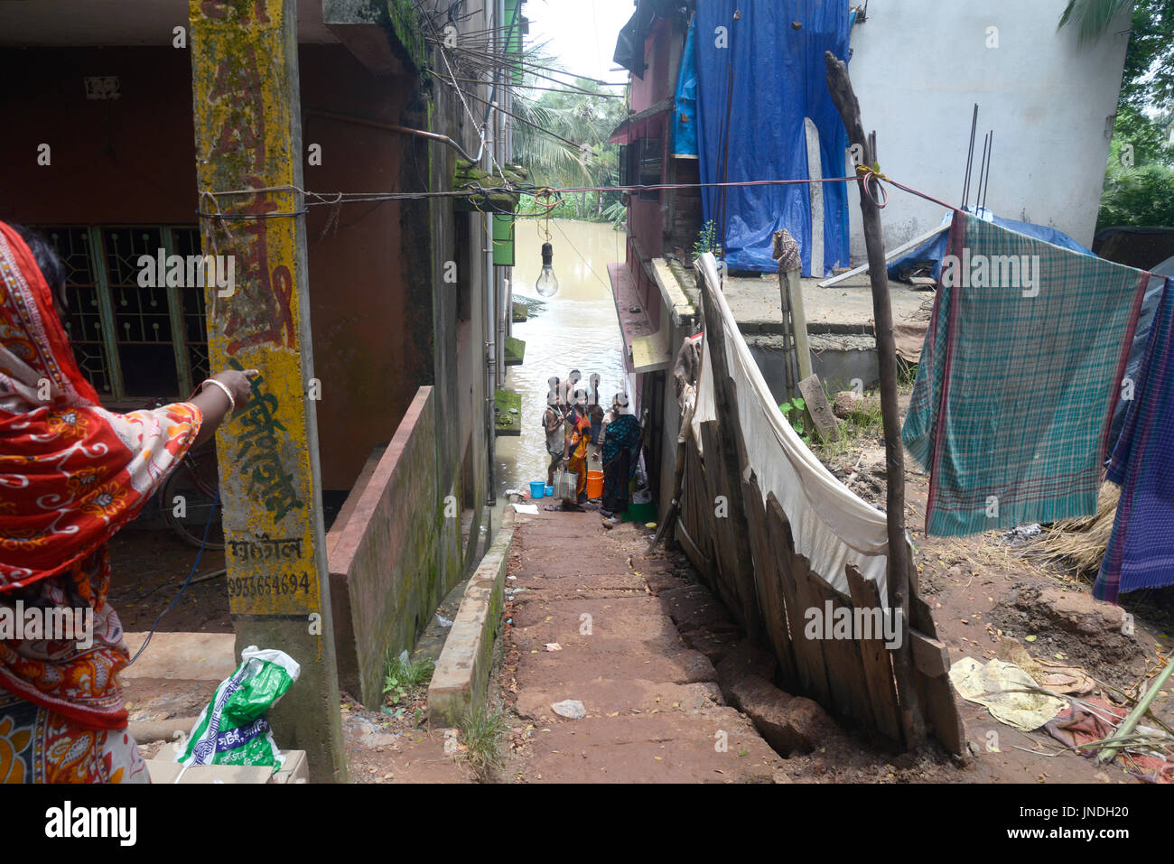 Ghatal, India. 29th July, 2017. Woman show the highest water level ...