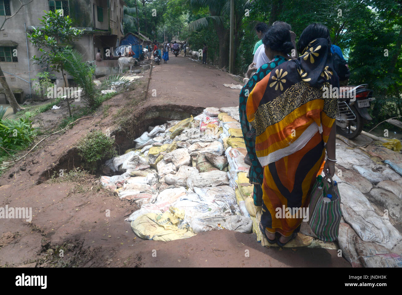 Ghatal, India. 29th July, 2017. Women cross the repaired part of river ...