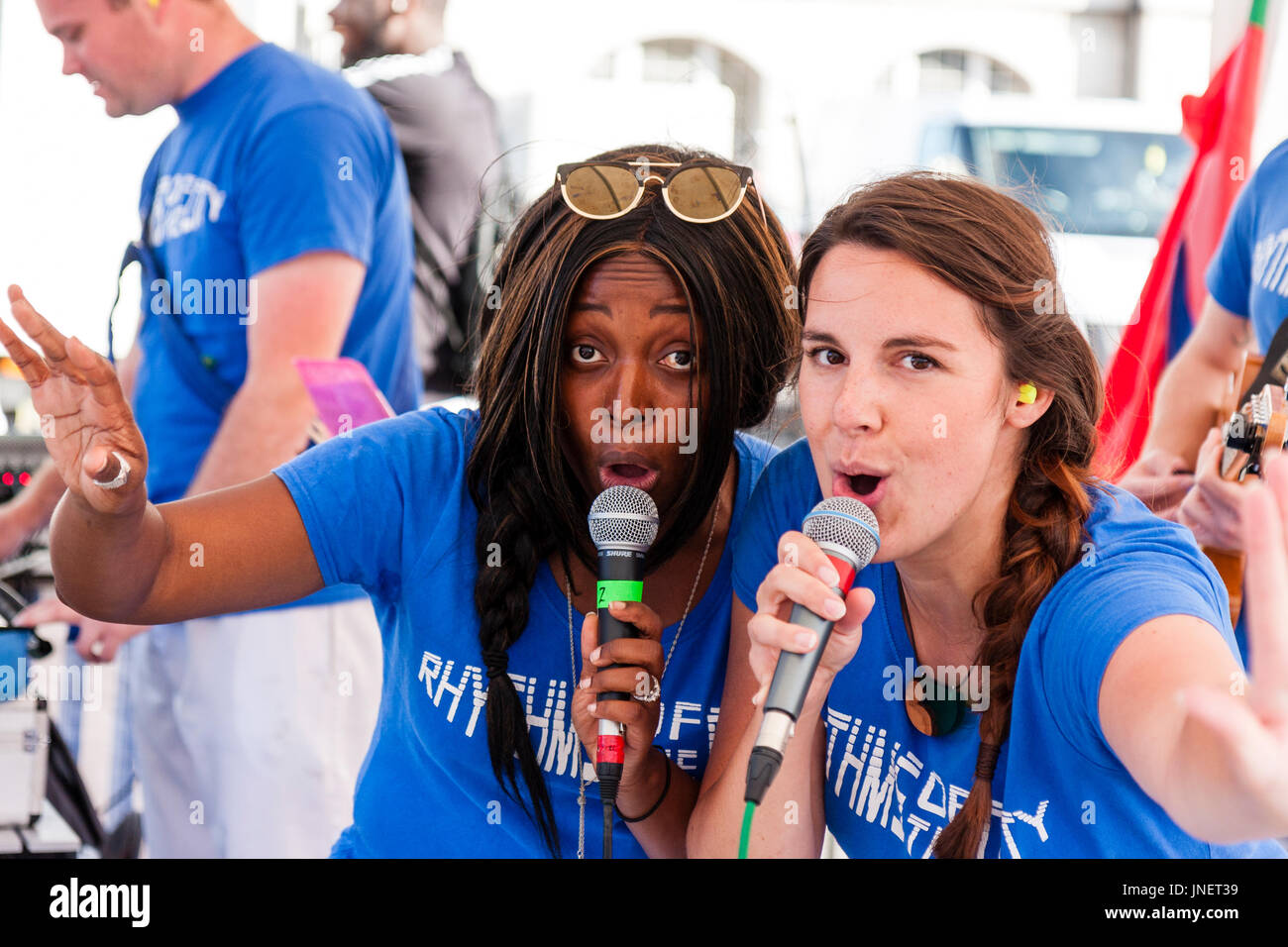 Two young women singers, one Afro-Caribbean, other Caucasian, holding ...