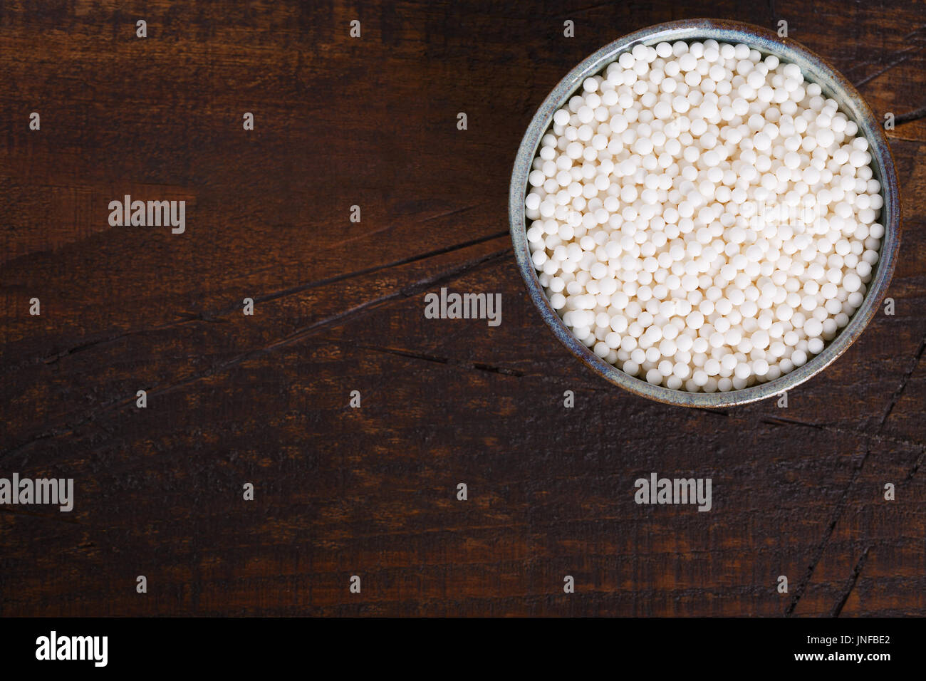 Granulated cassava (tapioca) on wooden background. Selective focus.Copy ...