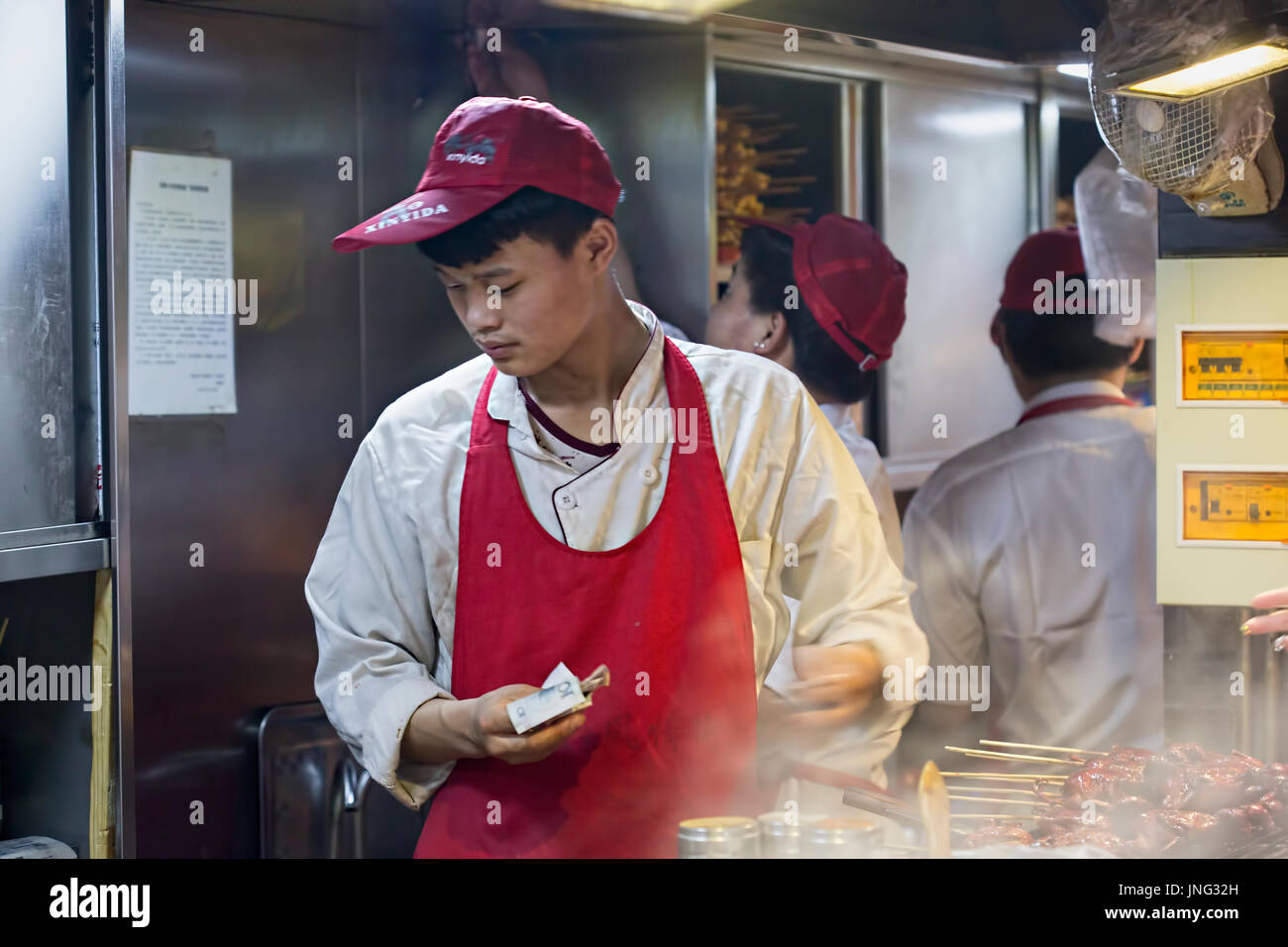 Chinese salesman preparing meat on traditional food market. Wangfujing ...