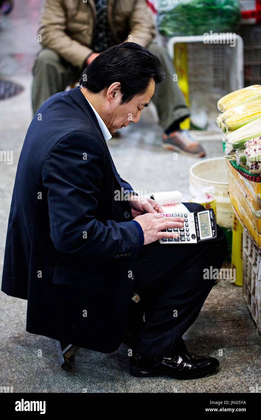 Chinese salesman in suit, sitting, calculating invoices, Beijing, China ...