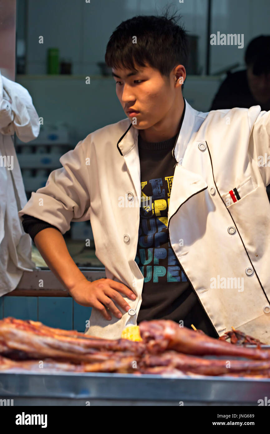 Chinese salesman preparing meat on traditional food market. Wangfujing ...