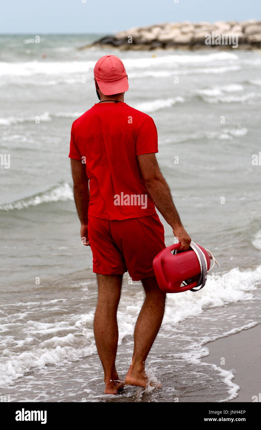 Lifeguard with red uniform controls bathers with stormy sea Stock Photo ...
