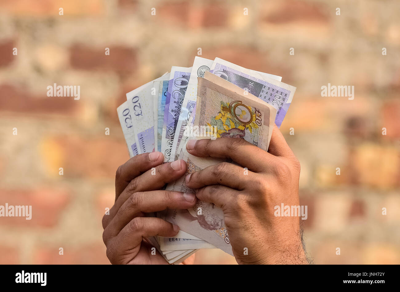 Counting Twenty pounds notes on brick wall background Stock Photo - Alamy