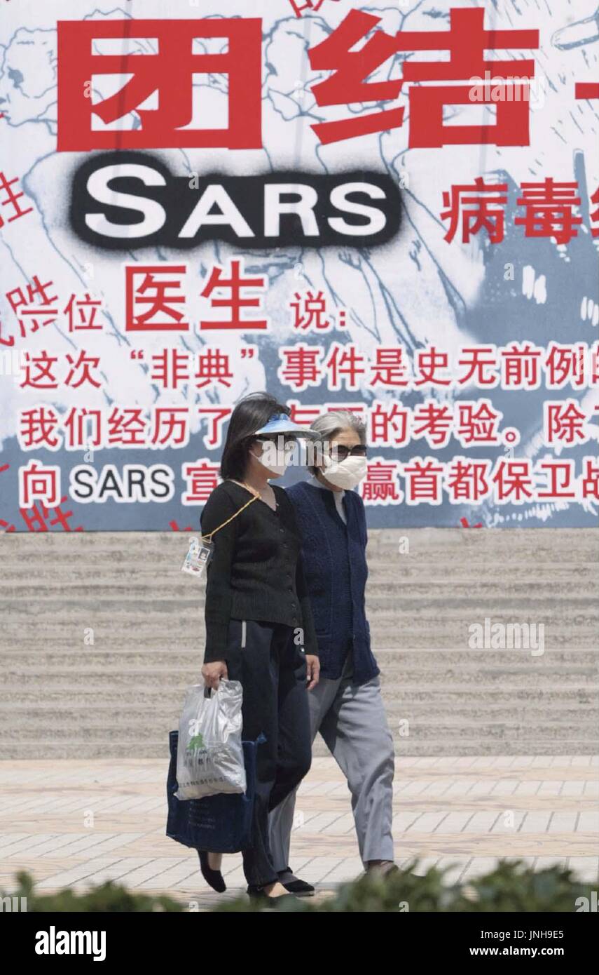 BEIJING, China - Two mask-wearing women walk by a huge banner urging ...