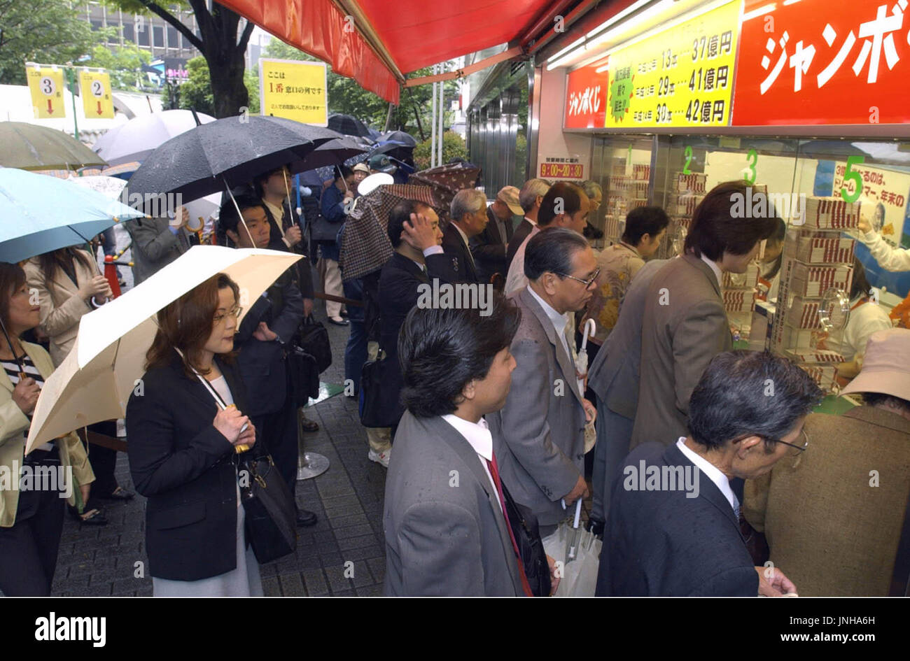 TOKYO, Japan - People form long queues in the rain in front of lottery ...