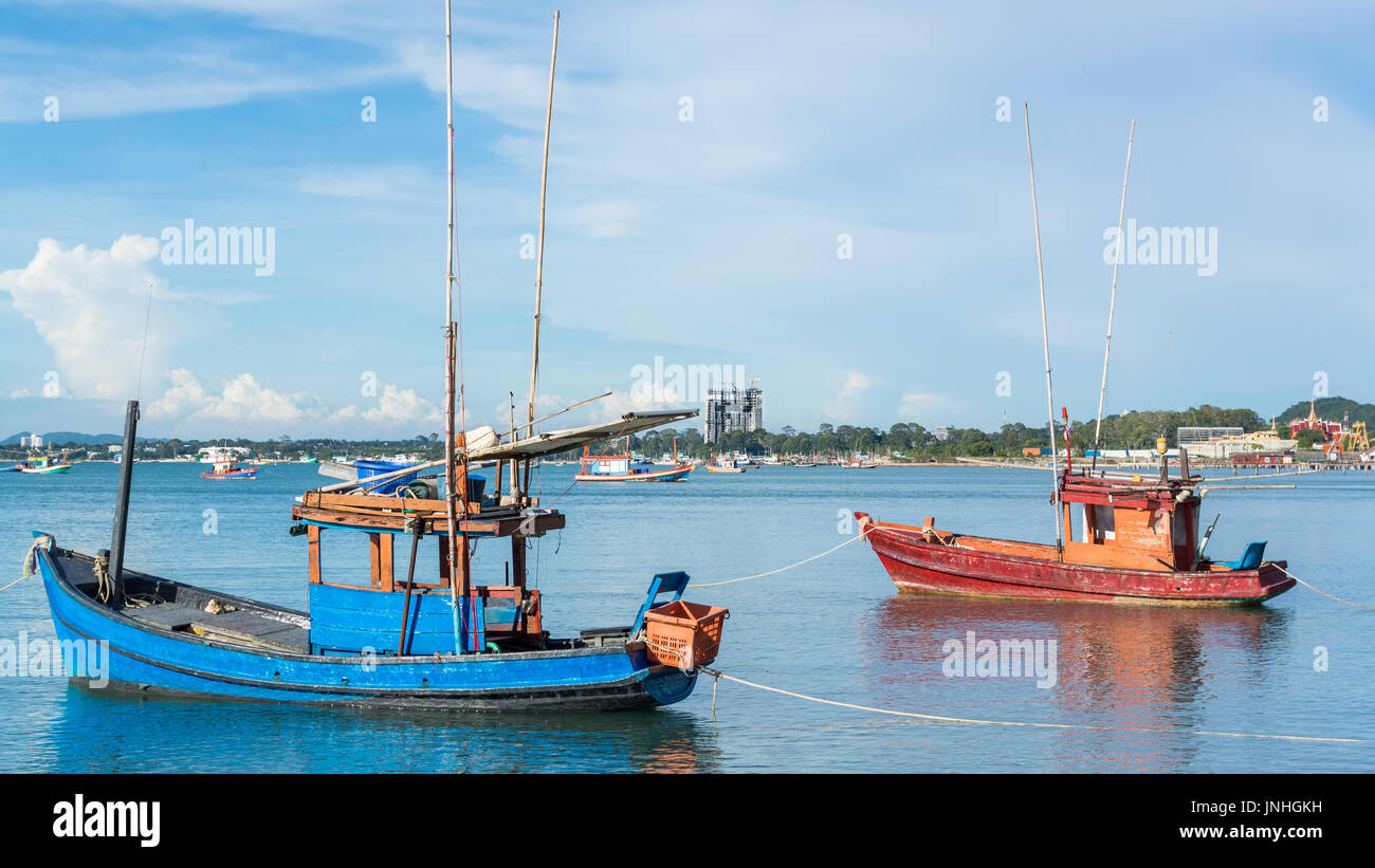 two boats floating on a blue calm sea at a tropical beach with a city ...