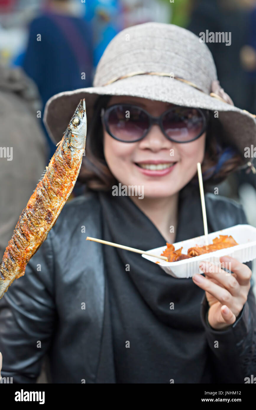 Chinese woman in sunglasses showing bought fish and seafood. Wangfujing ...