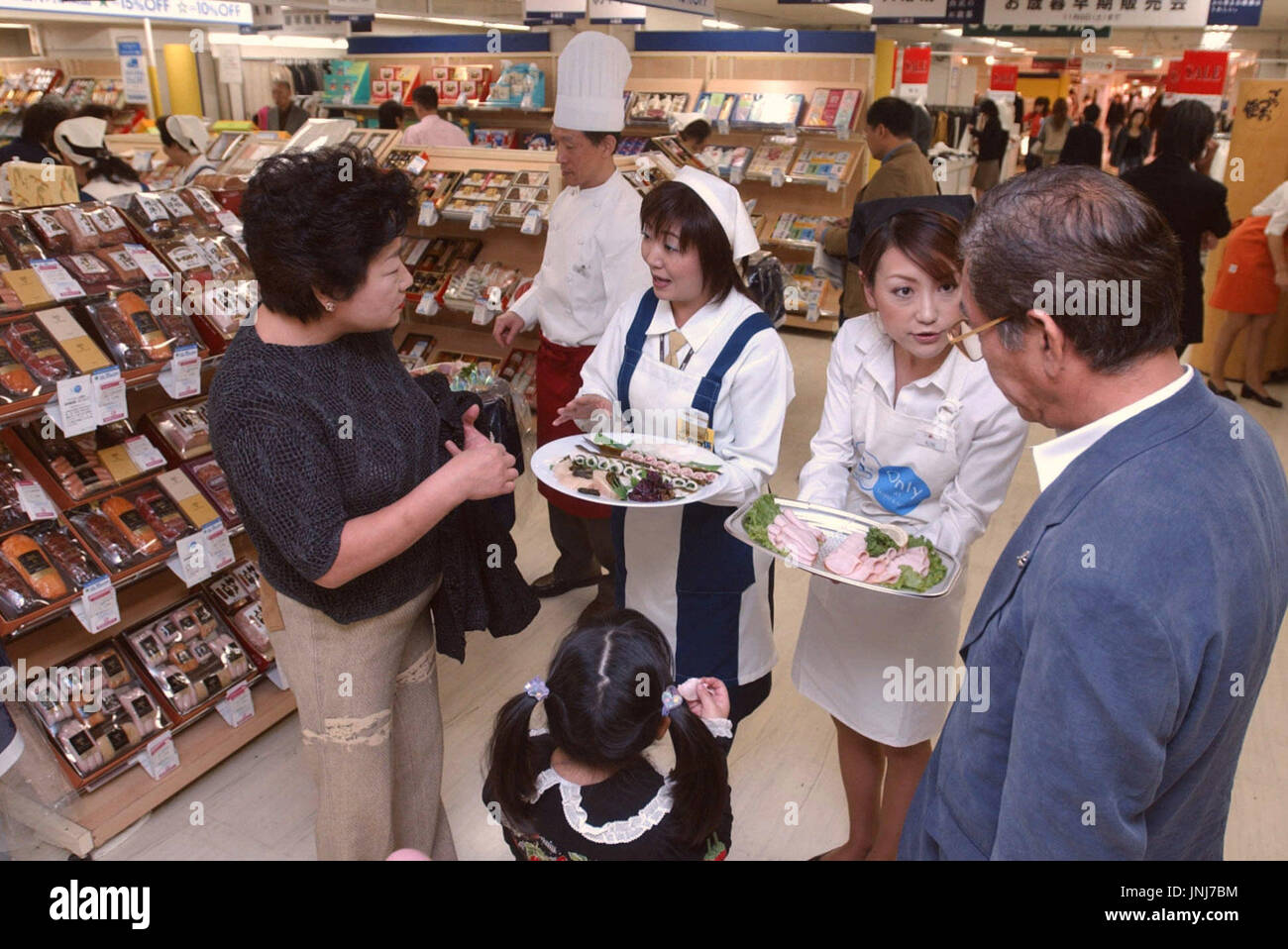 TOKYO, Japan - Shop assistants invite shoppers to taste samples at a ...