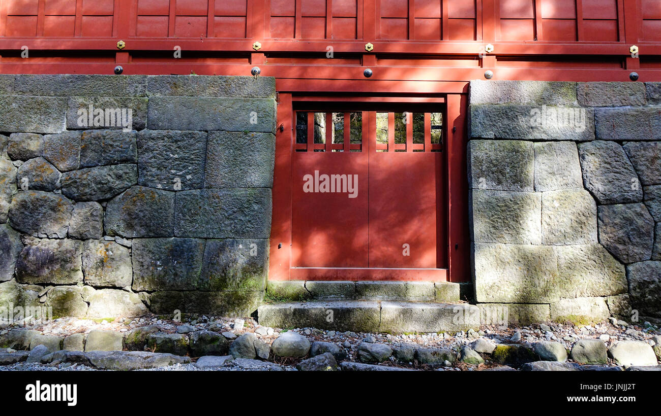 Red wooden door with stone wall at an ancient shrine in Japan Stock ...