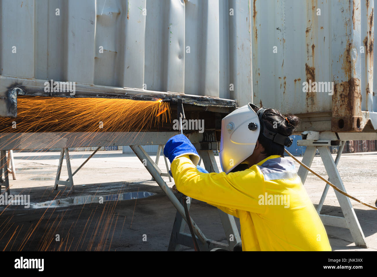 Industry worker with protective mask welding steel to repair container ...