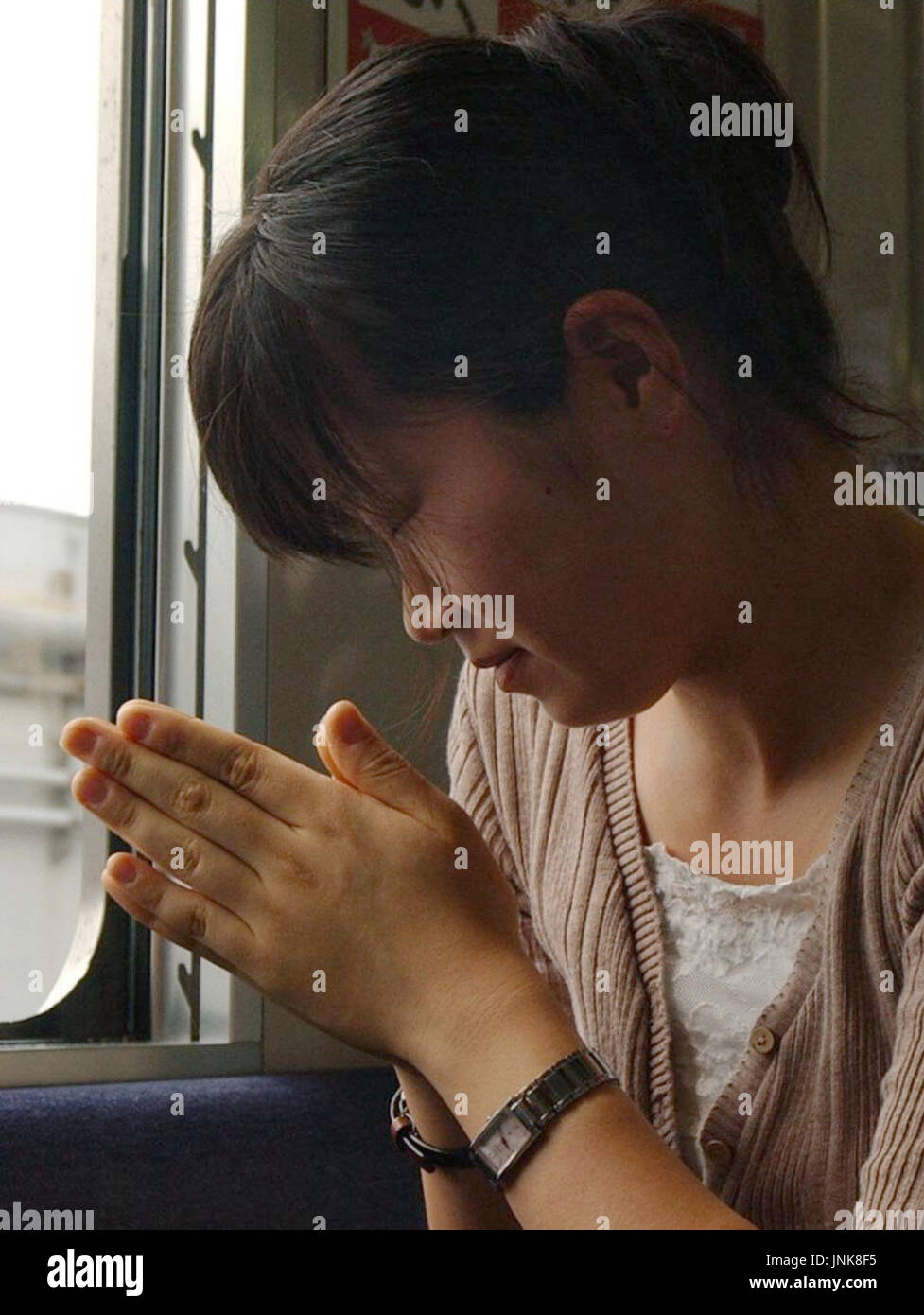 AMAGASAKI, Japan - A woman passenger on a West Japan Railway Co. train prays for the victims of ...