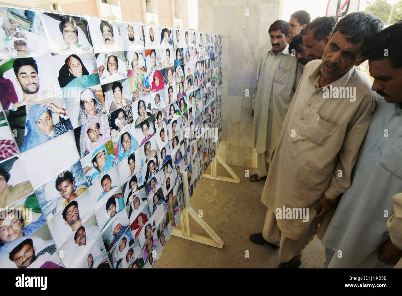 ISLAMABAD, Pakistan - People look at photos of victims taken to an ...