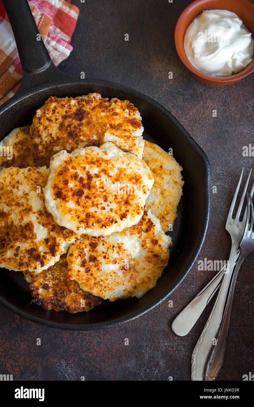 Rustic homemade curd pancakes in cast iron pan with yogurt sauce for ...