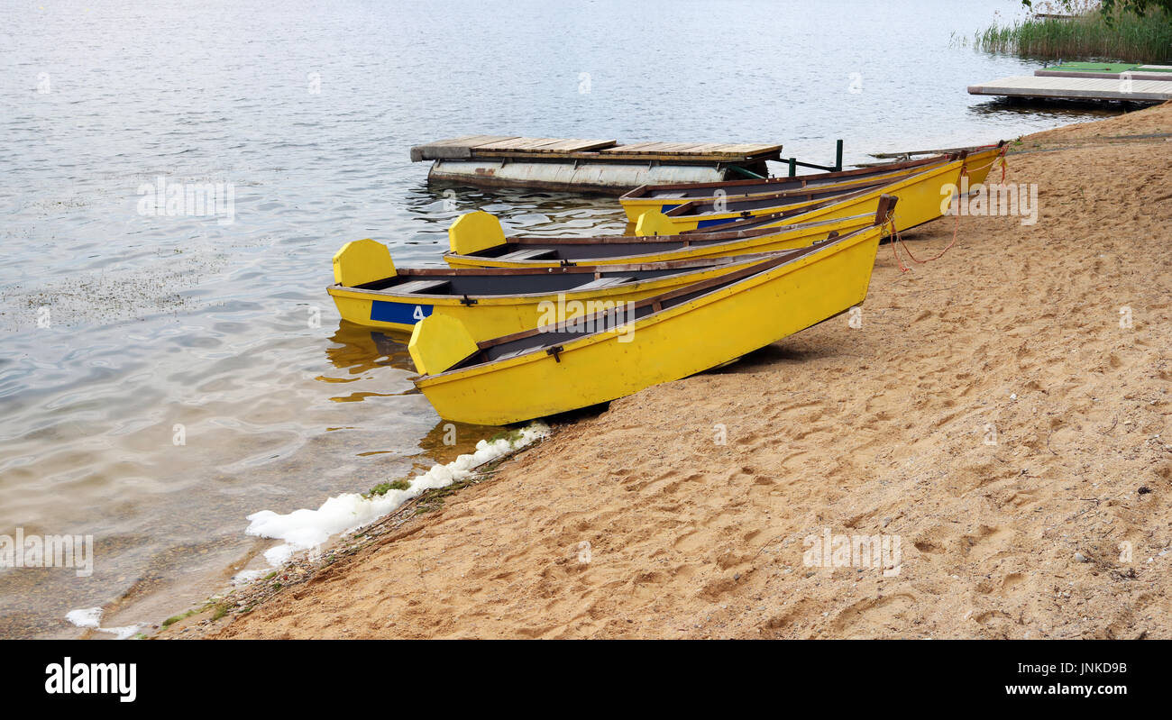 Wooden yellow aged used boats on cold fresh lake water. Sandy water ...