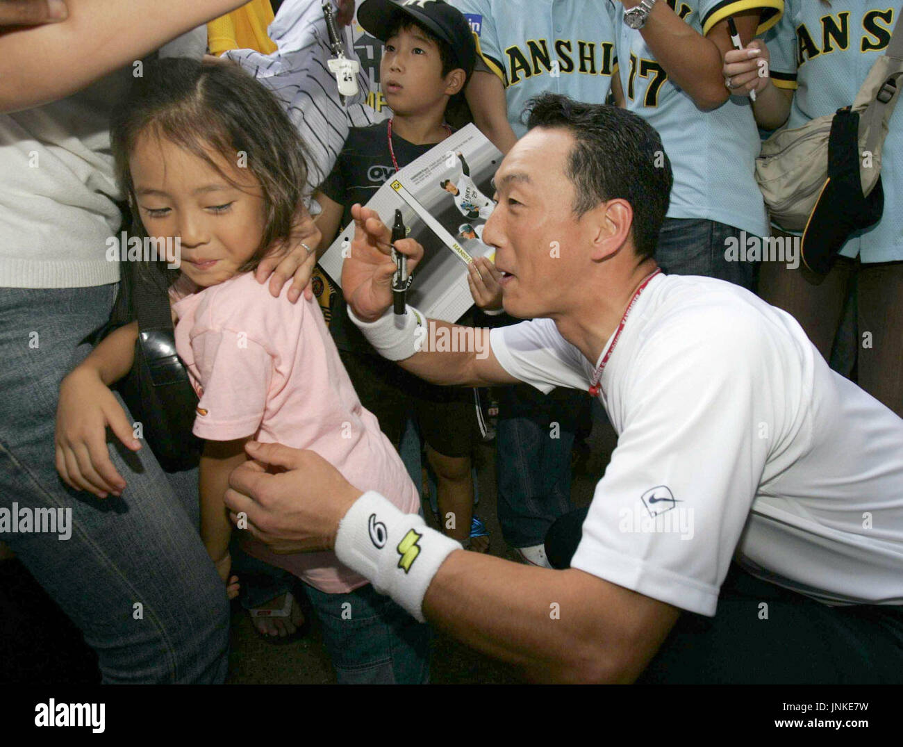 TOKYO, Japan - Hanshin Tigers outfielder Tomoaki Kanemoto puts his autograph on the back of a ...