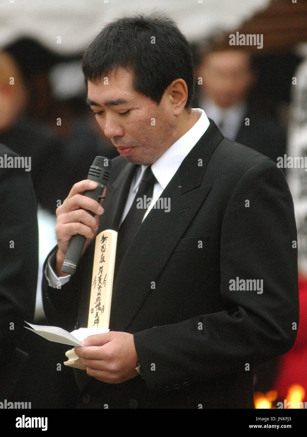 KOIDE, Japan - Manabu Minagawa speaks to mourners in front of his home ...