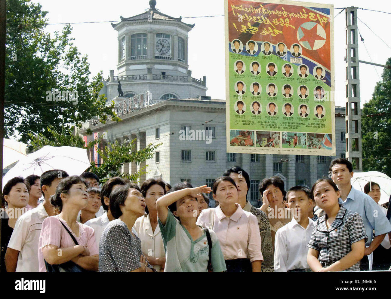 PYONGYANG, North Korea - Citizens look up at banners and posters ...