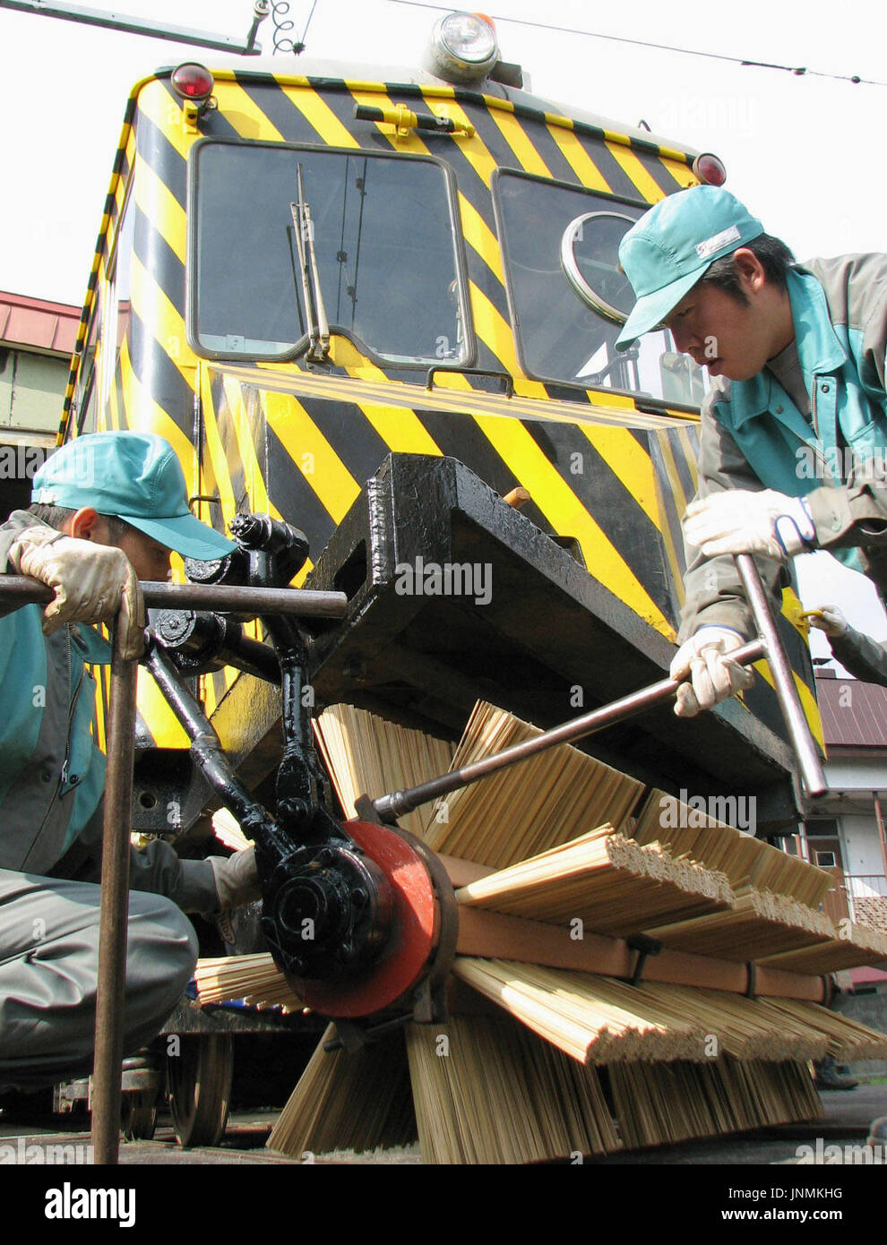 SAPPORO, Japan - Workers puts a snow-brushing gear on a street car in ...
