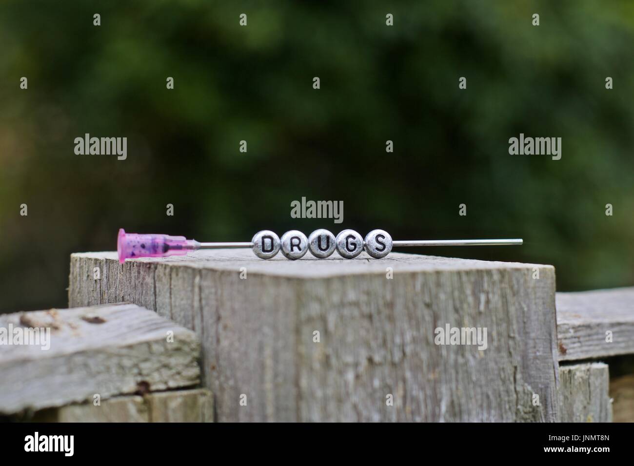 Long needle with sign drugs in green and wooden concept Stock Photo - Alamy