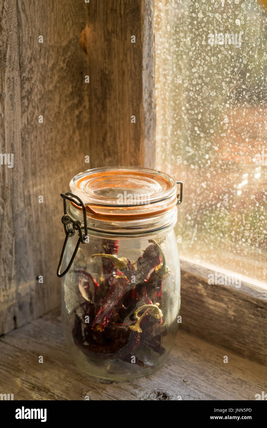 Chilli pepper in a glass jar on the sill of an old window Stock Photo ...