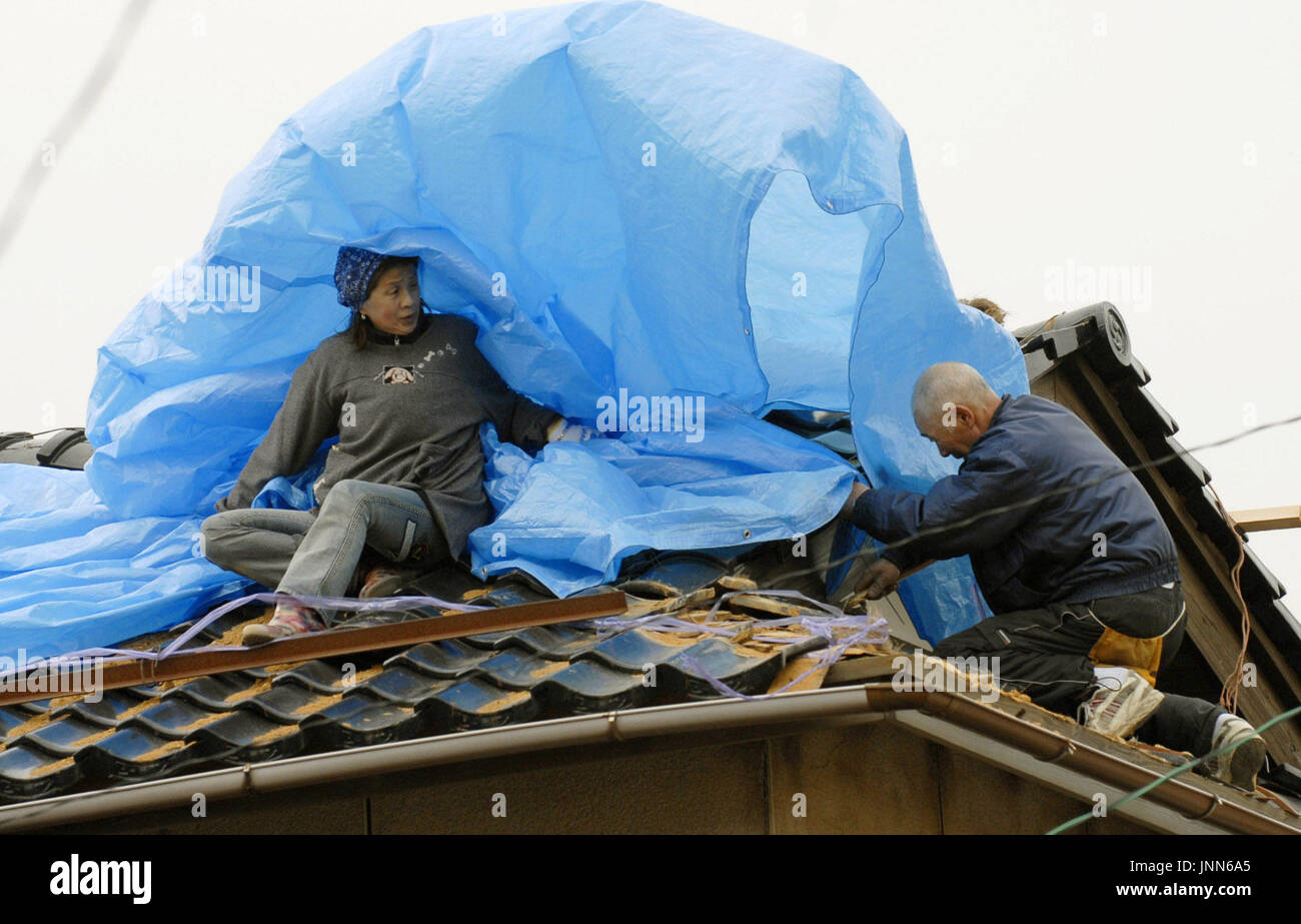 WAJIMA, Japan - As inclement weather approaches, workers cover the ...
