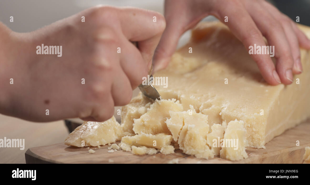 female hand cutting hard parmesan cheese Stock Photo - Alamy