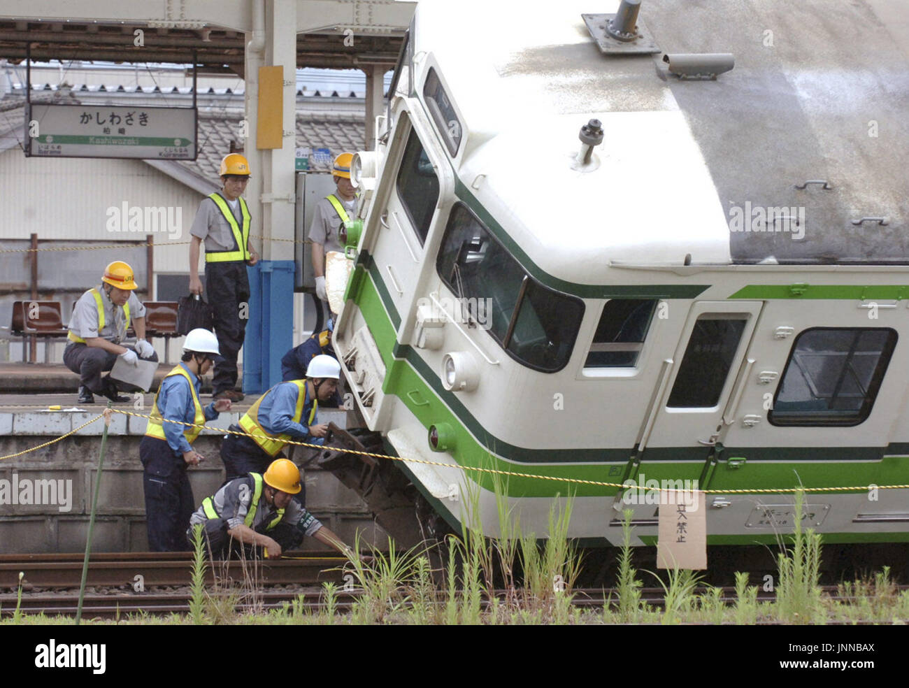 KASHIWAZAKI, Japan - Workers examine a derailed train car at JR ...