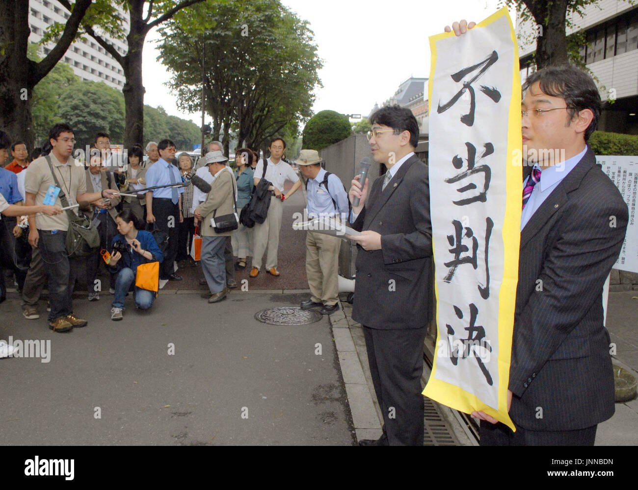 TOKYO, Japan - A plaintiff lawyer speaks to reporters outside the Tokyo ...