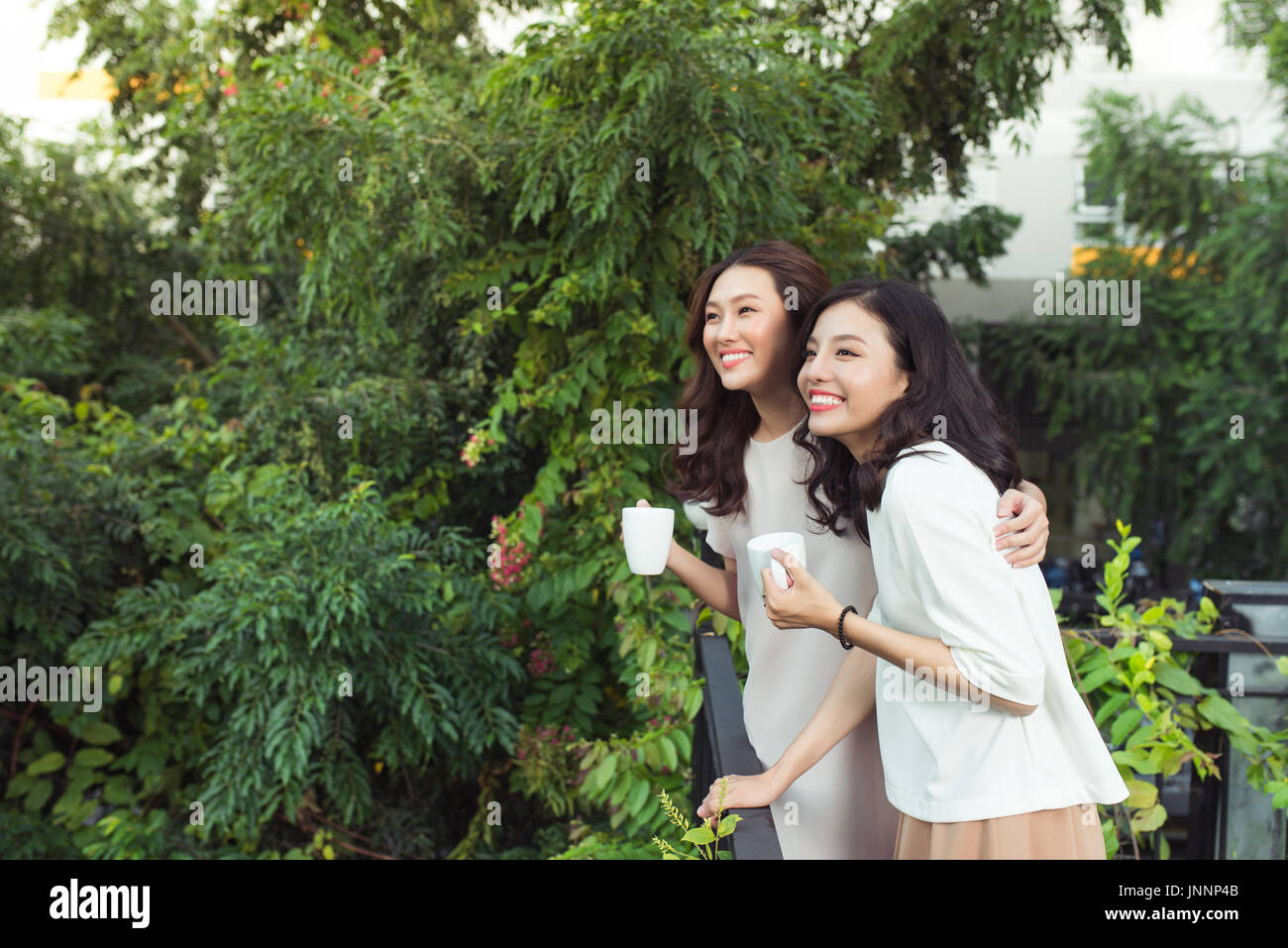 Happy young women friends well-dressed smiling while standing together ...