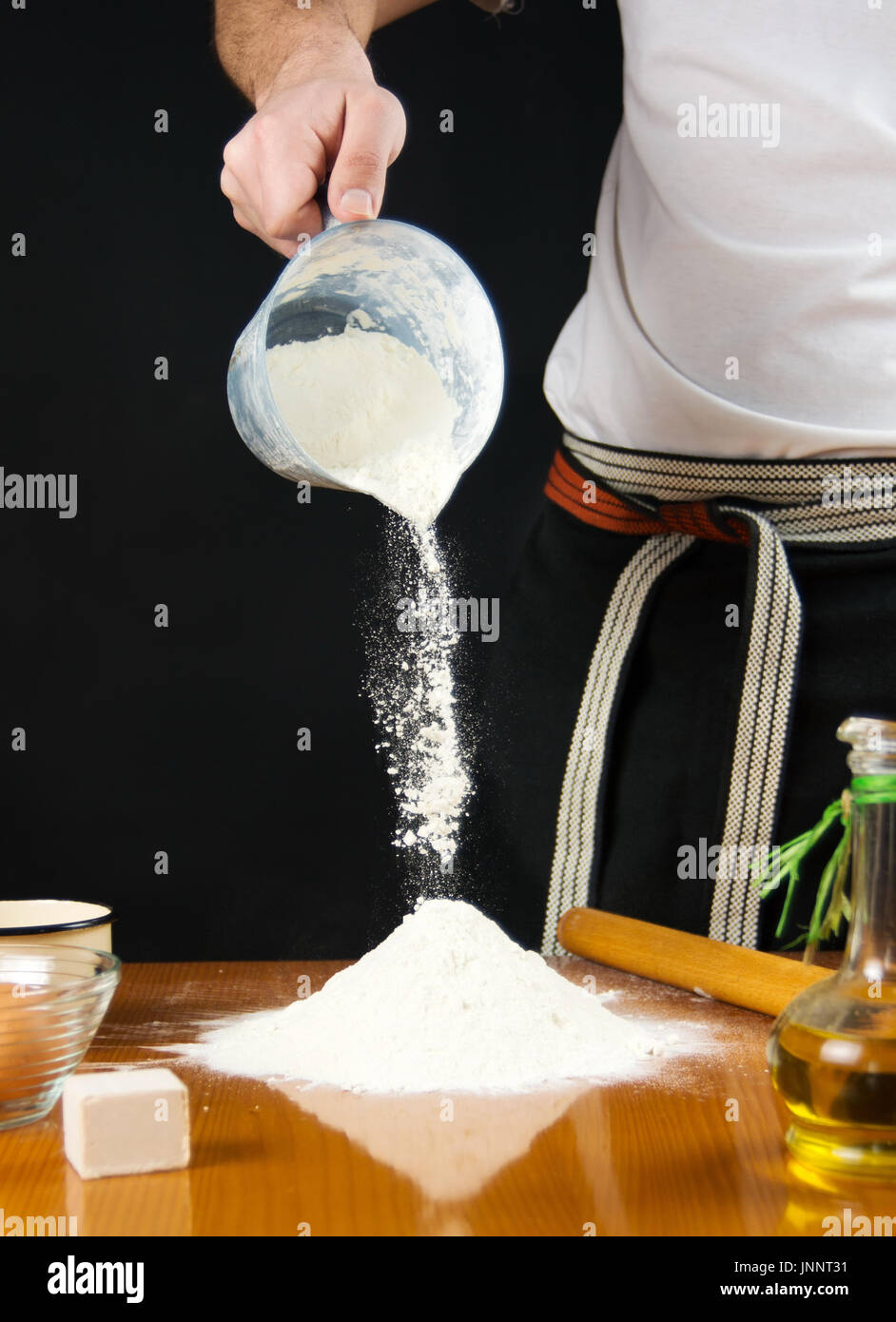 Man pouring flour from the measure bowl on the table Stock Photo - Alamy