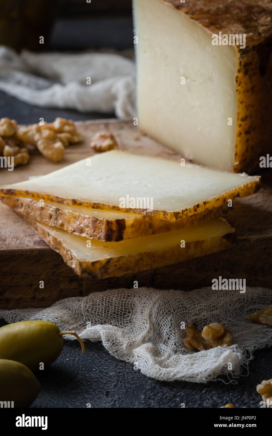 Italian hard cheese pecorino toscano sliced on wooden board with green ...