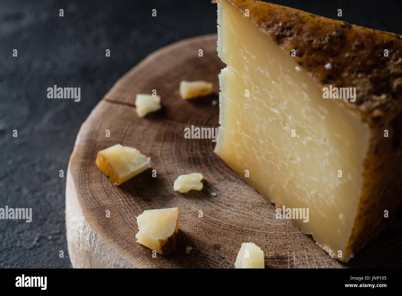 Italian hard cheese pecorino toscano chopped on wooden cut on dark ...